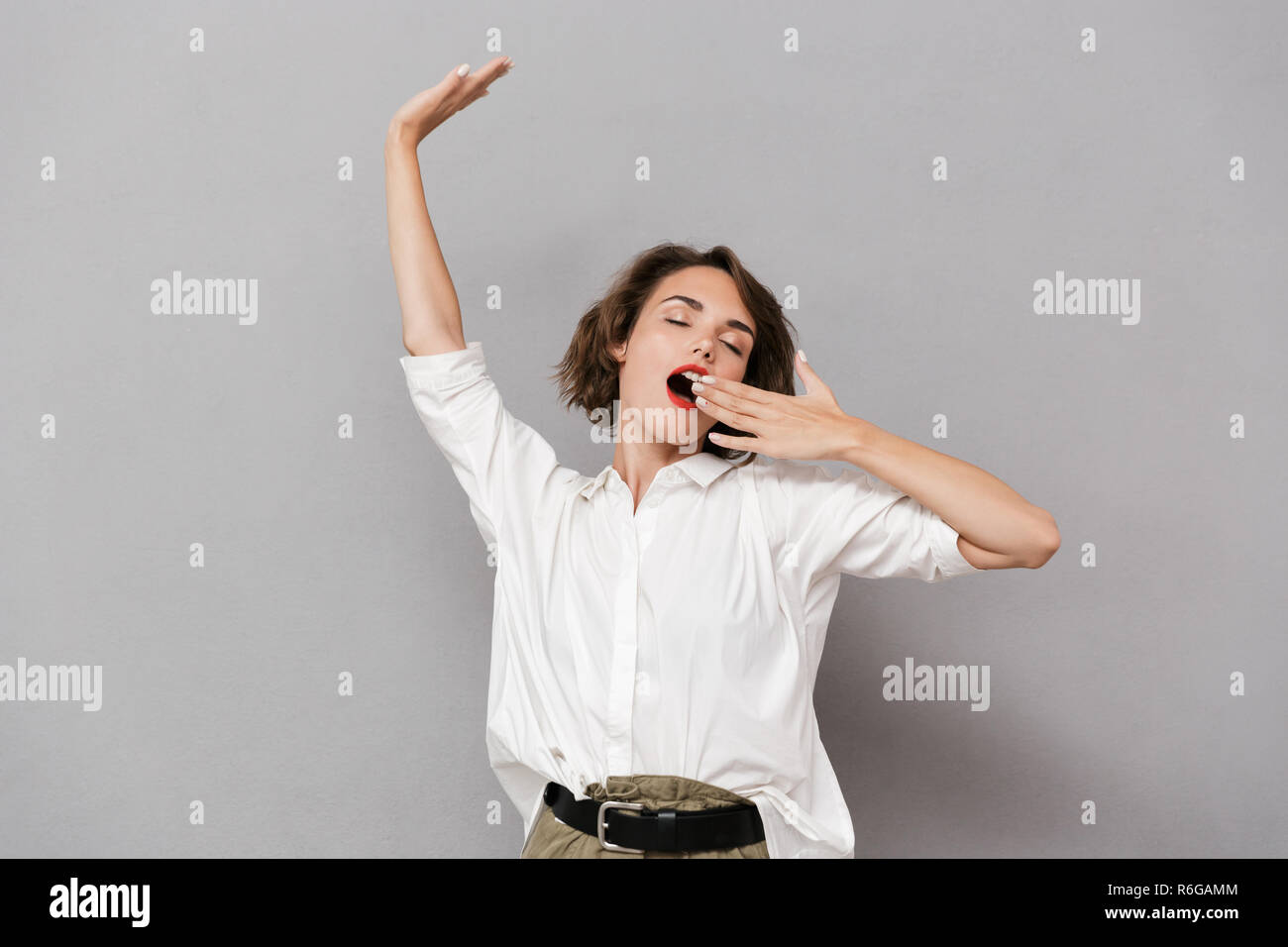 Portrait of a smiling young woman standing isolated over gray ...