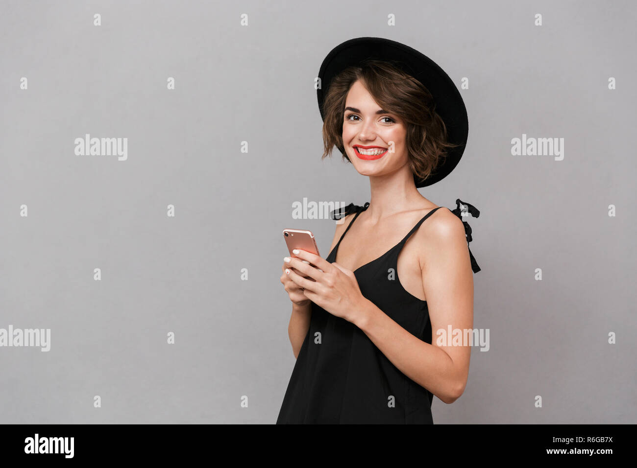 Photo of beautiful woman 20s wearing black dress and hat smiling at ...