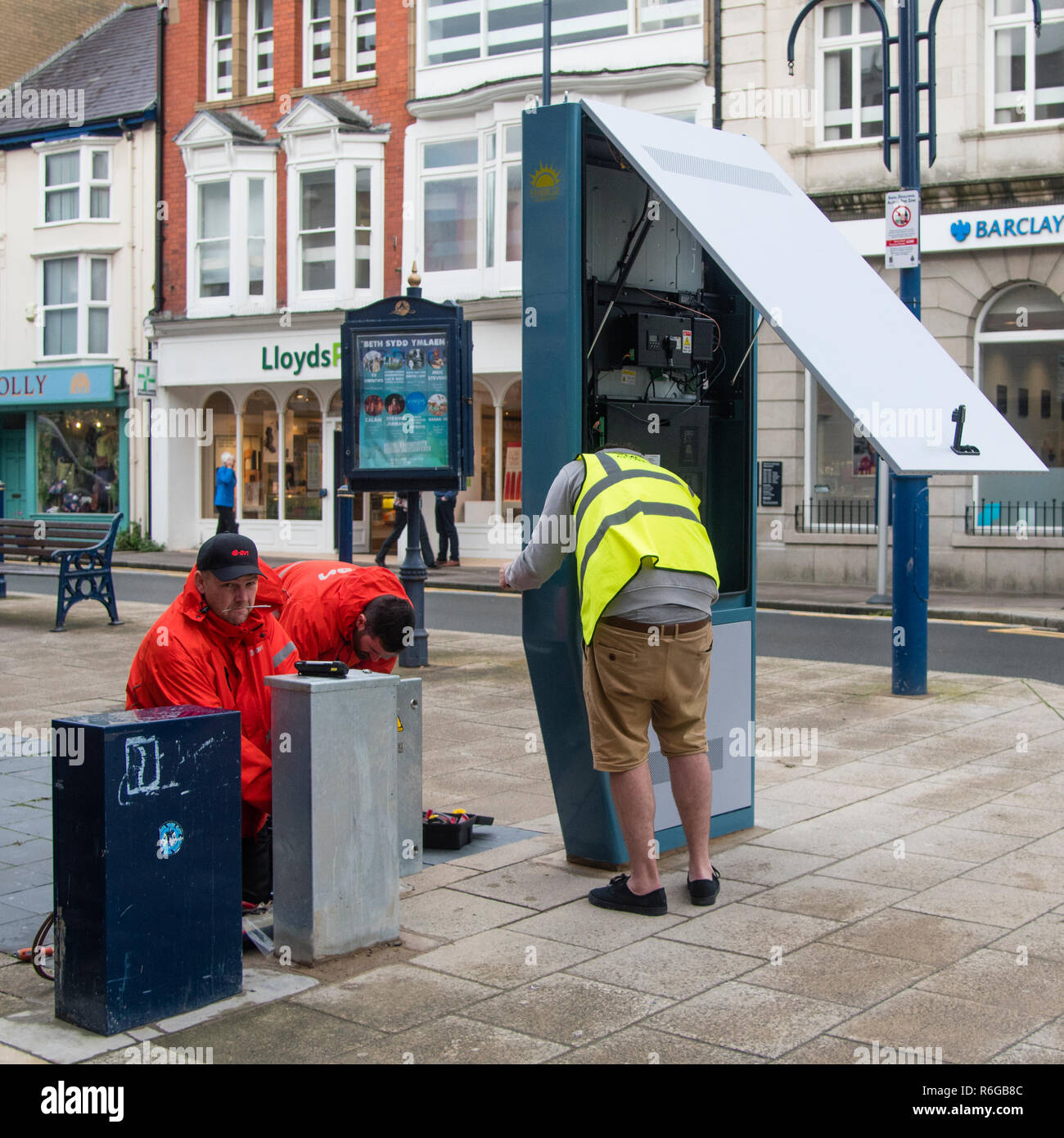 Workmen installing a new high-tech digital advertising display kiosk on ...