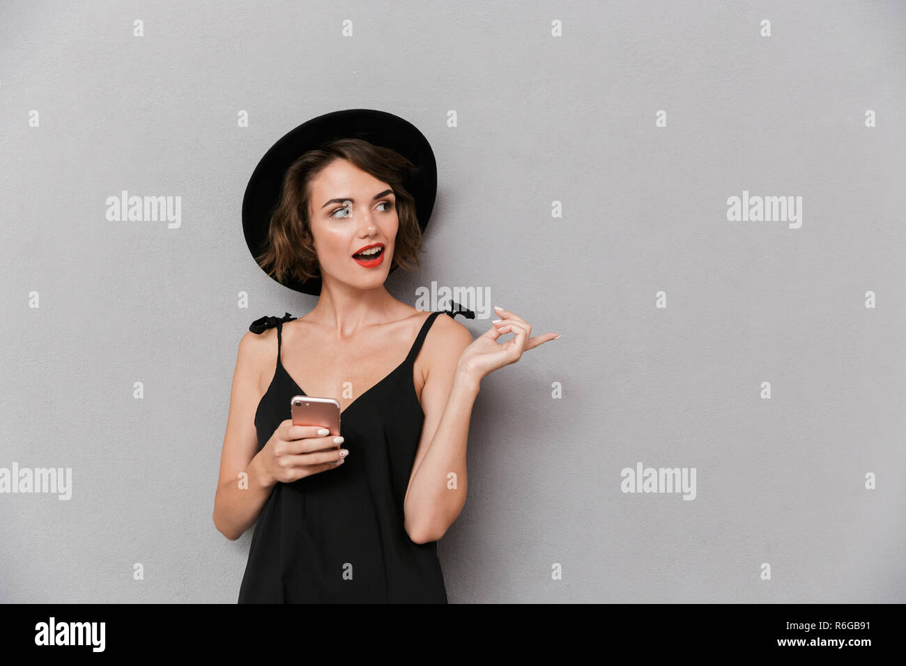 Photo of beautiful woman 20s wearing black dress and hat smiling at ...