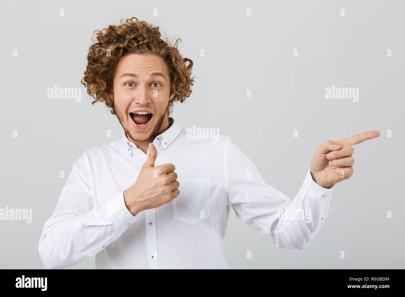 Portrait of a cheerful young man with curly hair isolated over white ...