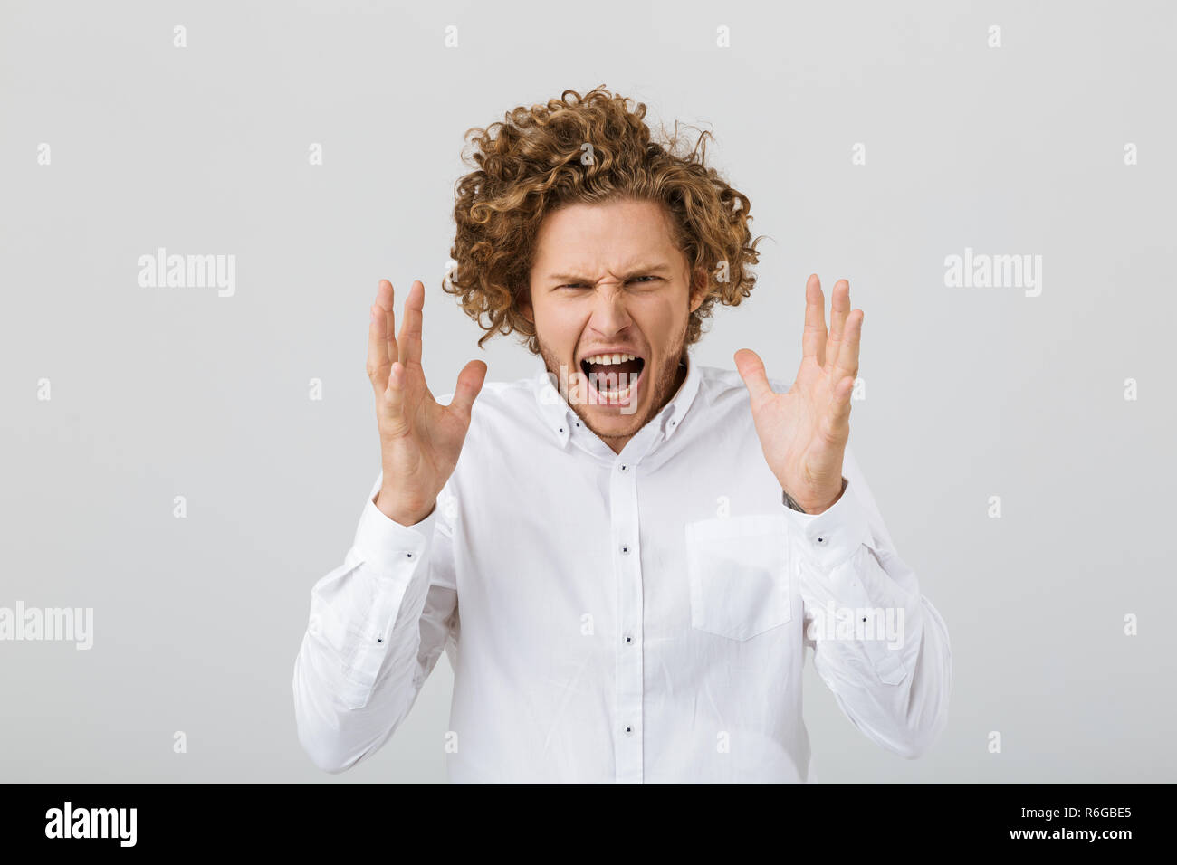 Portrait of a mad young man with curly hair isolated over white ...