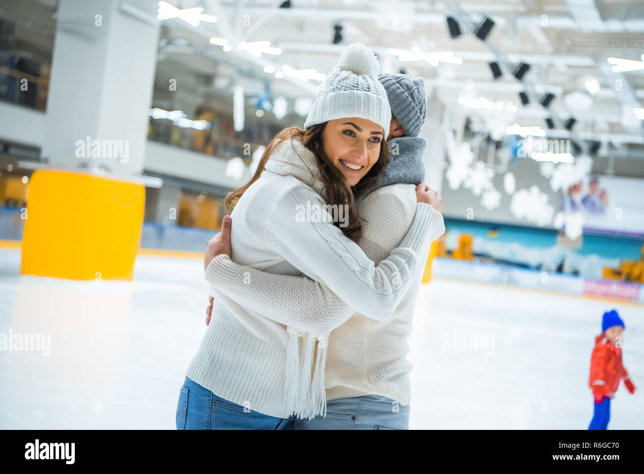 side view of couple in love hugging while skating on ice rink together ...