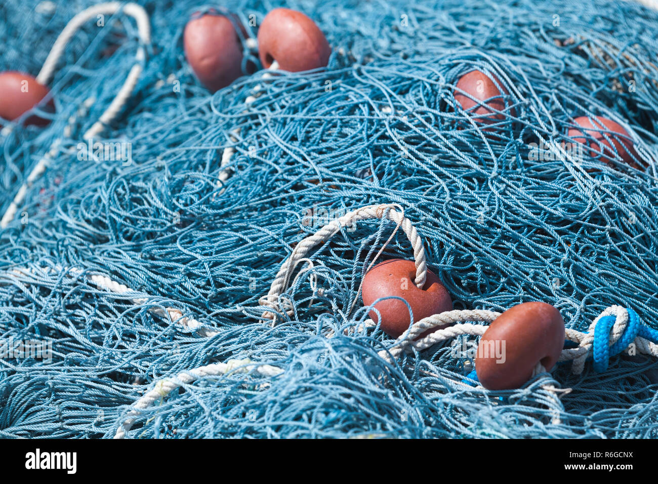 Blue fishing net with red floats lays in port. Close-up background ...