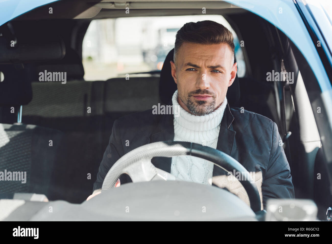 Handsome man in sweater and jacket sitting in car Stock Photo - Alamy
