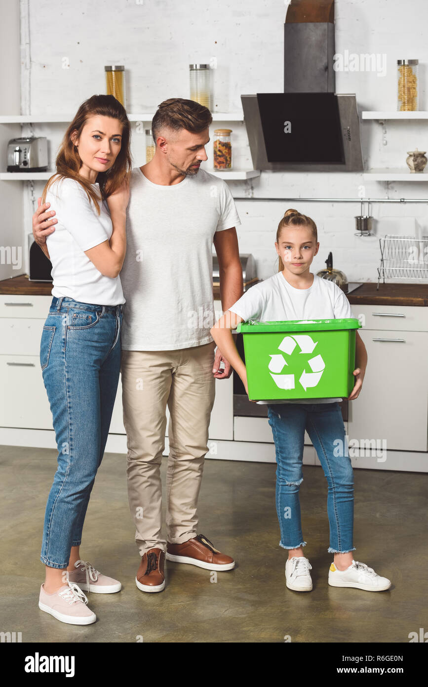 parents standing at kitchen while daughter holding green box with ...