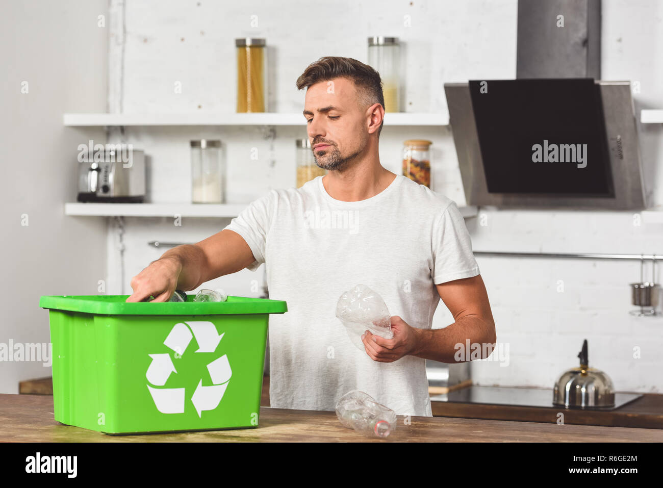 handsome man putting plastic bottles in green recycle box Stock Photo ...