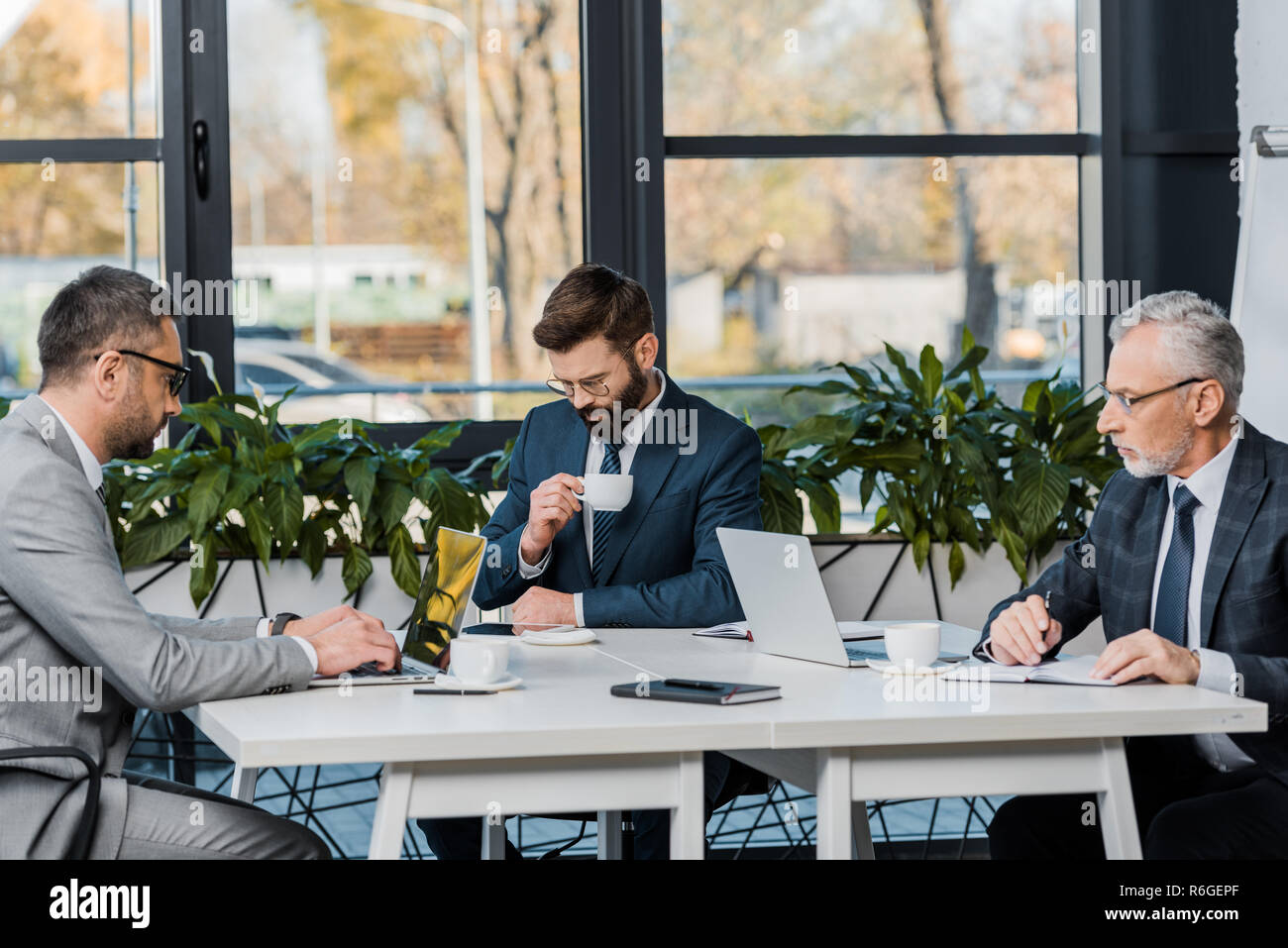 three professional businessmen in formal wear working with digital ...