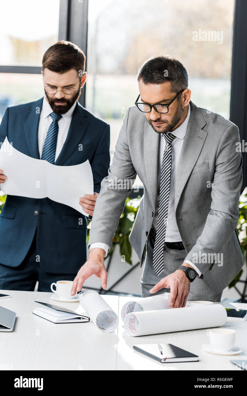 serious professional businessmen working with papers and blueprints in ...