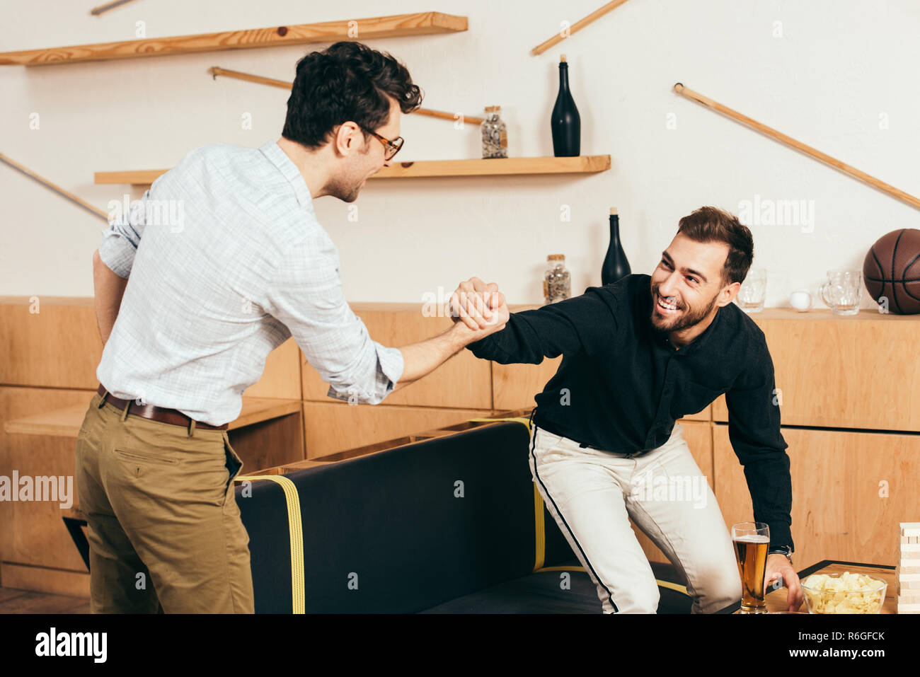 smiling friends shaking hands while greeting each other in cafe Stock ...