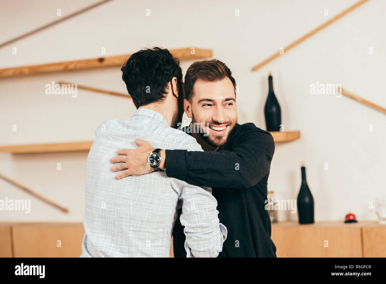 friends hugging while greeting each other in cafe Stock Photo - Alamy