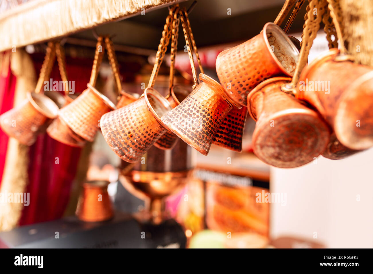 Close up of a bunch of copper coffee jezve pots hanged up in a market ...