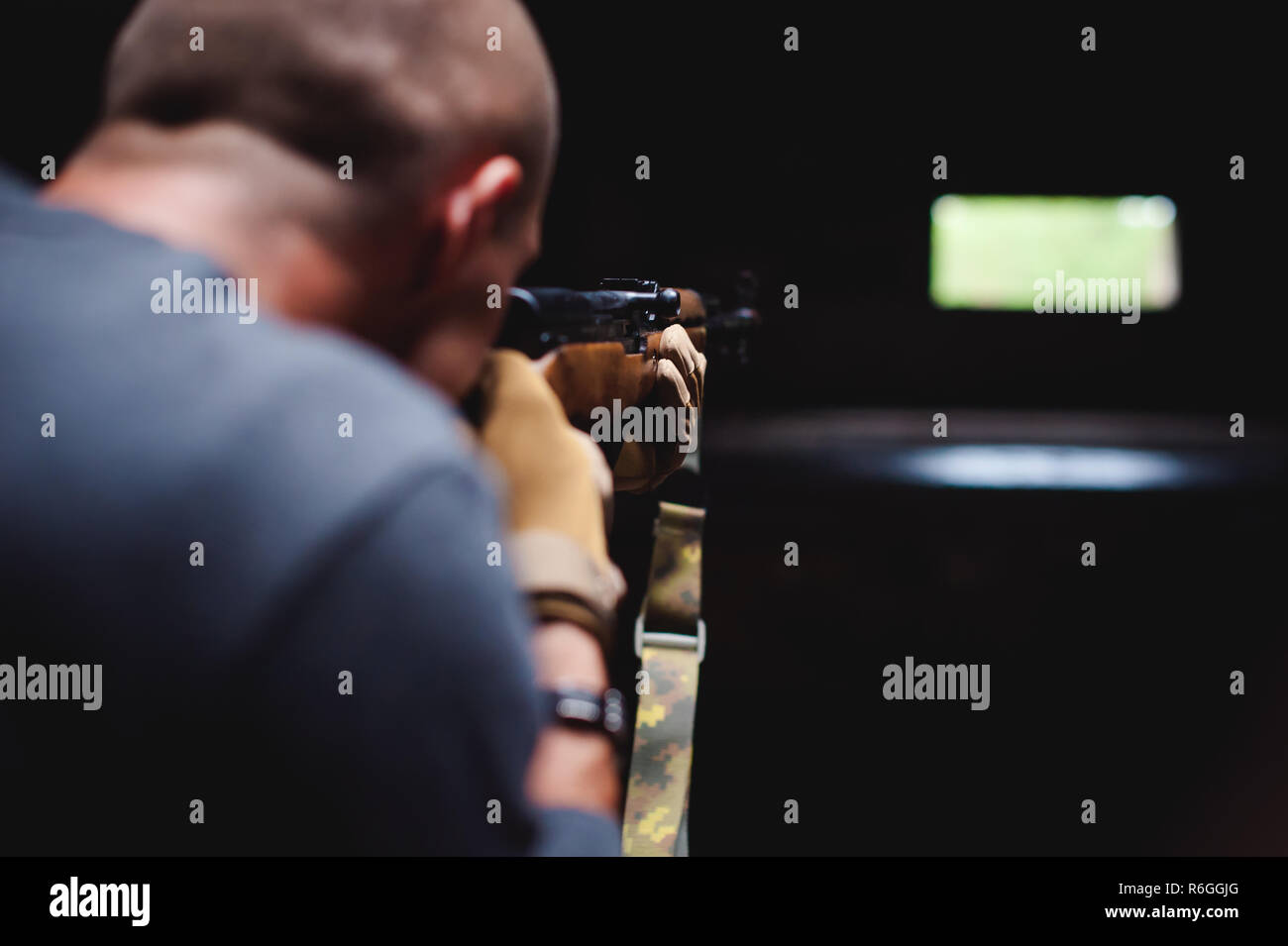 Athletic man in gray clothes with a carbine gun in his hand. Close-up ...