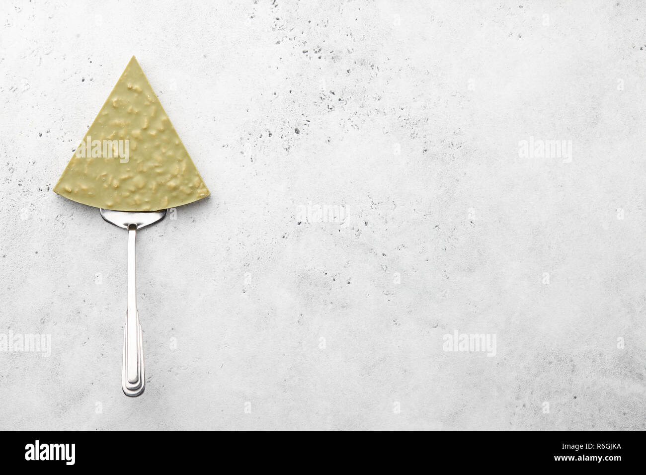Triangle chocolate piece on spatula on stone background Stock Photo - Alamy