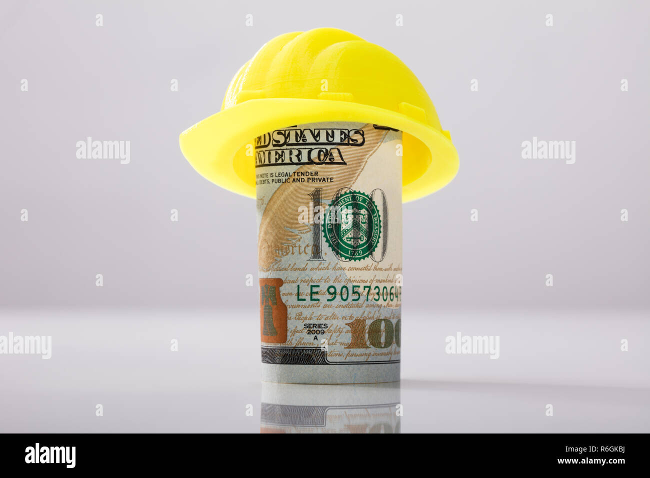 Yellow Hard Hat Over Rolled Up American Banknote Stock Photo - Alamy