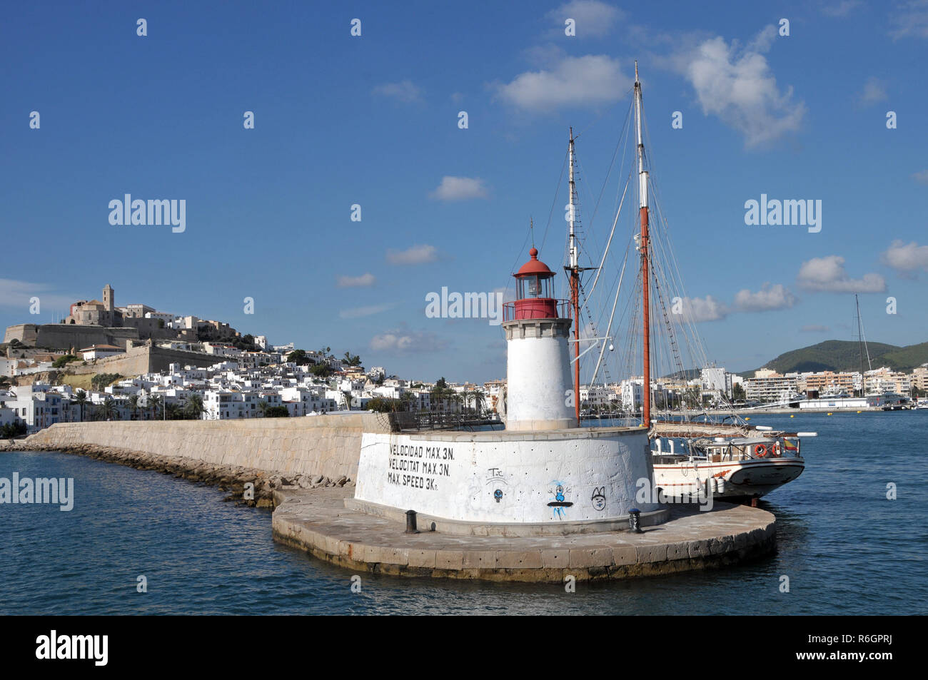 lighthouse at the harbor entrance with castle hill of ibiza town Stock ...