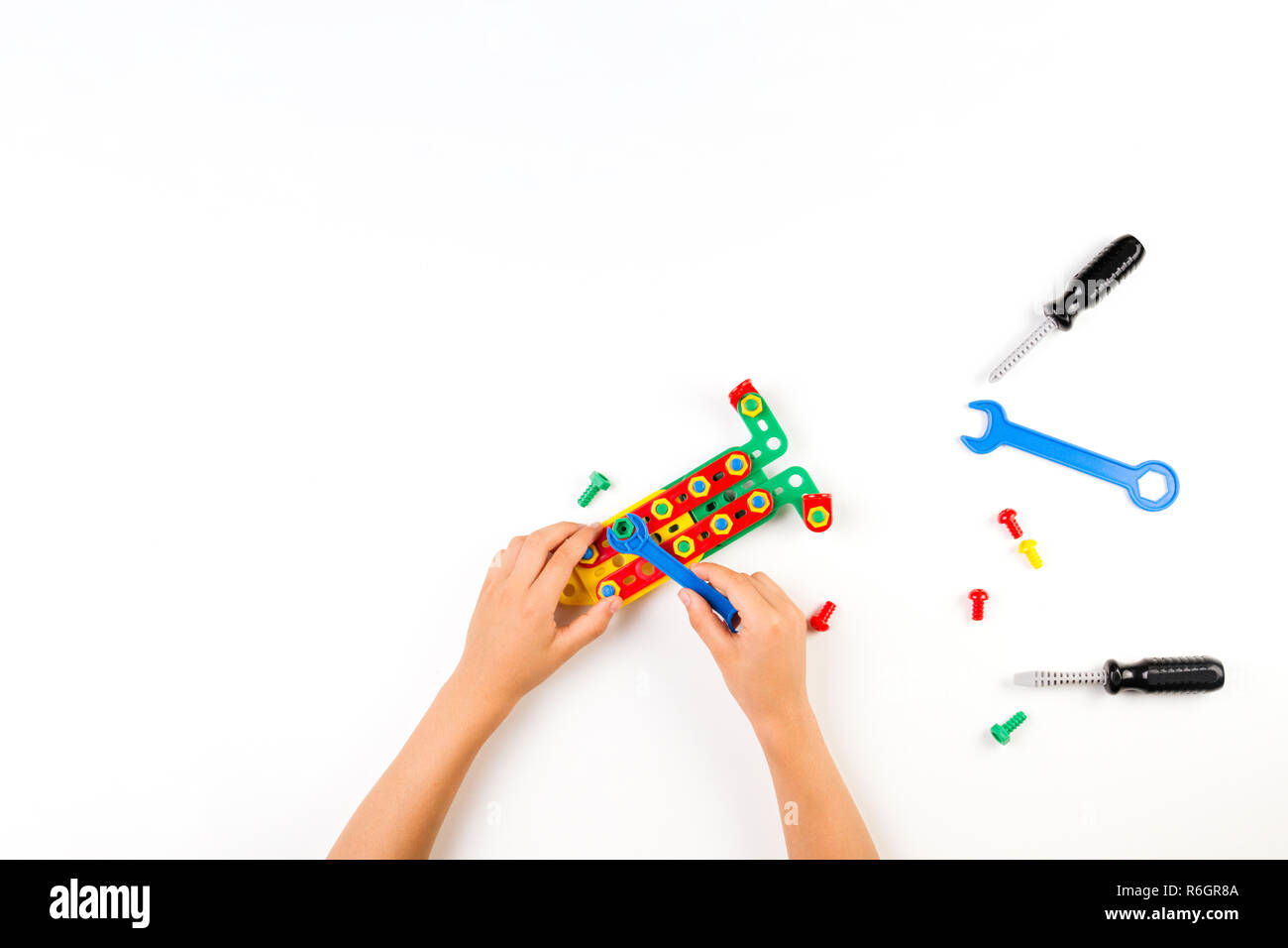 Child's hands playing with colorful toys tools on the white background ...