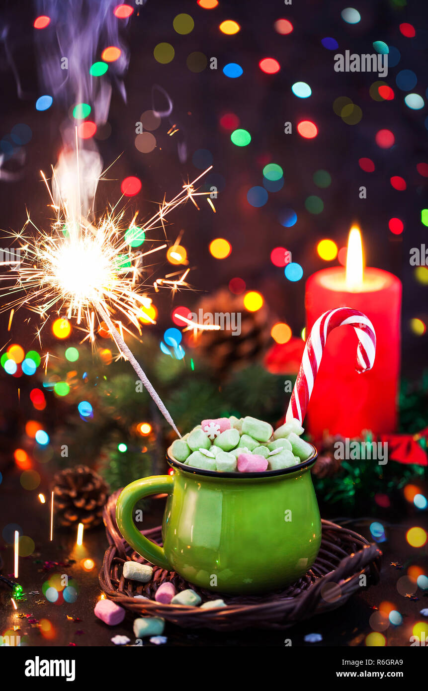 Green mug of hot chocolate with marshmallows, candy cane and sparkler ...