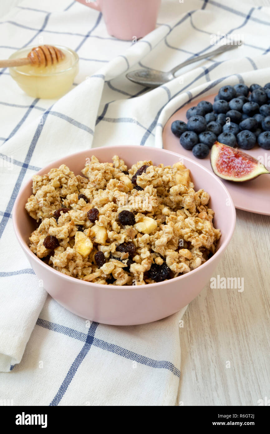 Pink bowl of fruit granola with fruits and honey, side view. Close-up ...