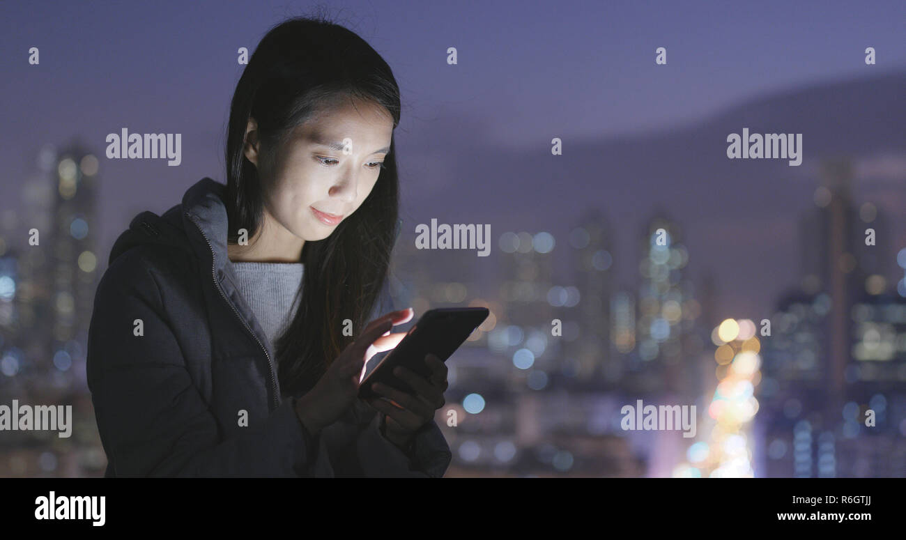 Woman using mobile phone over city at night Stock Photo - Alamy