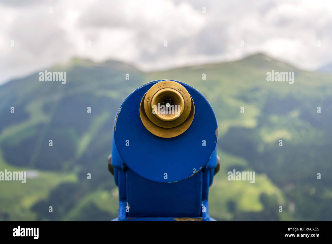 Public telescope arrayed against mountain range Alps in Austria, cloudy ...