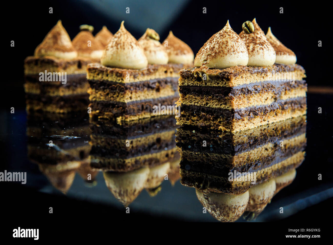 Opera cake slices on black mirror background Stock Photo - Alamy