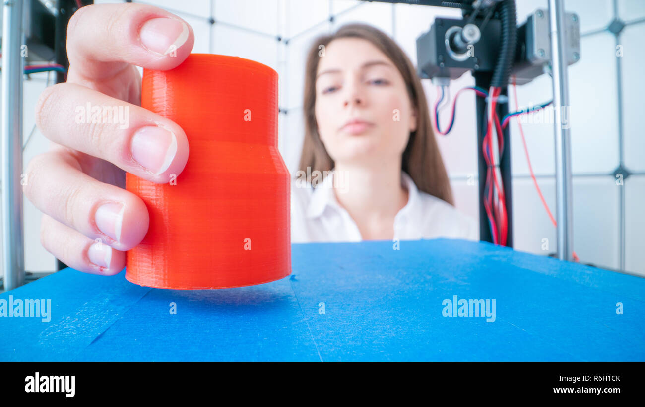 Young women designer in 3d printing lab. Girl takes the finished detail ...