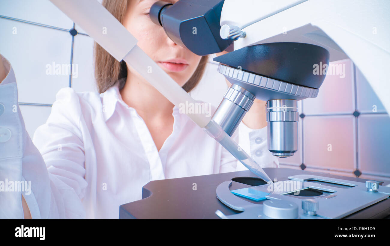 Scientist analyzing microscope slide at laboratory. Young woman ...