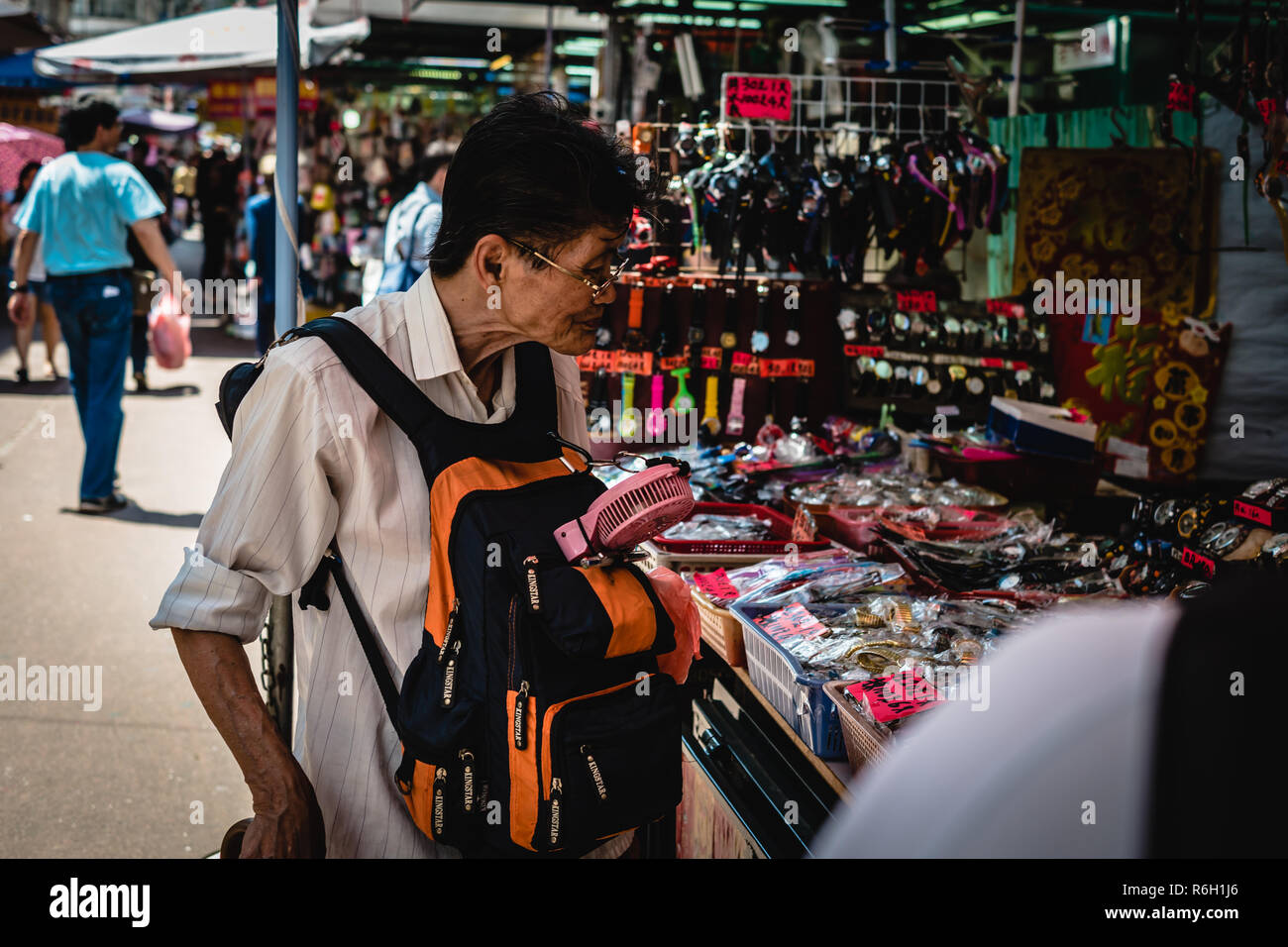 An old man is watching some stuff at a street market in Hong Kong Stock ...