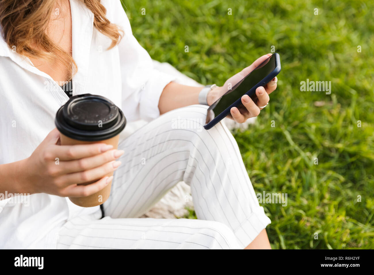 Close up of a woman spending time at the park, sitting on a grass ...