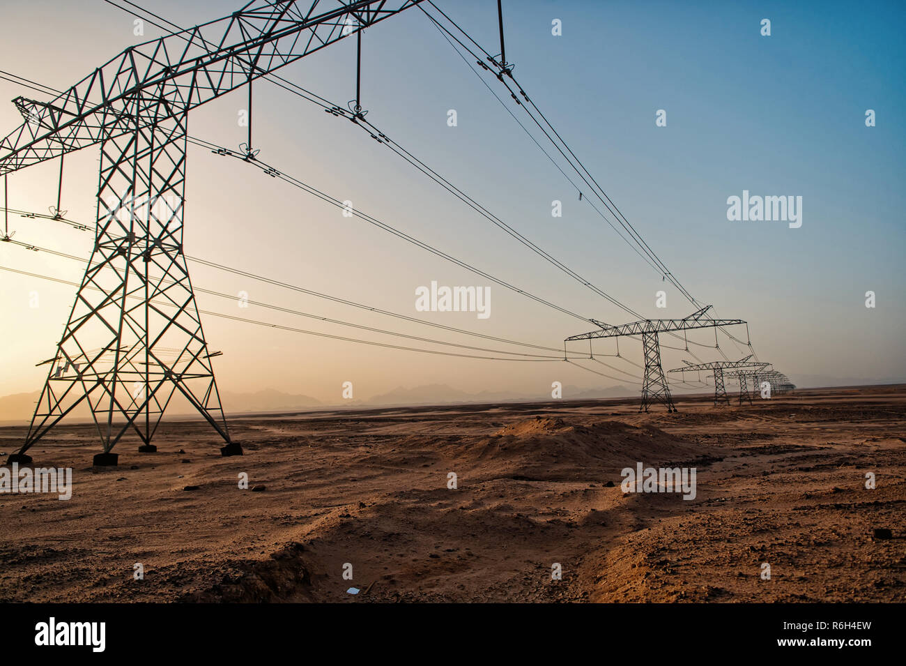 High voltage power lines in desert valley on blue sky background ...