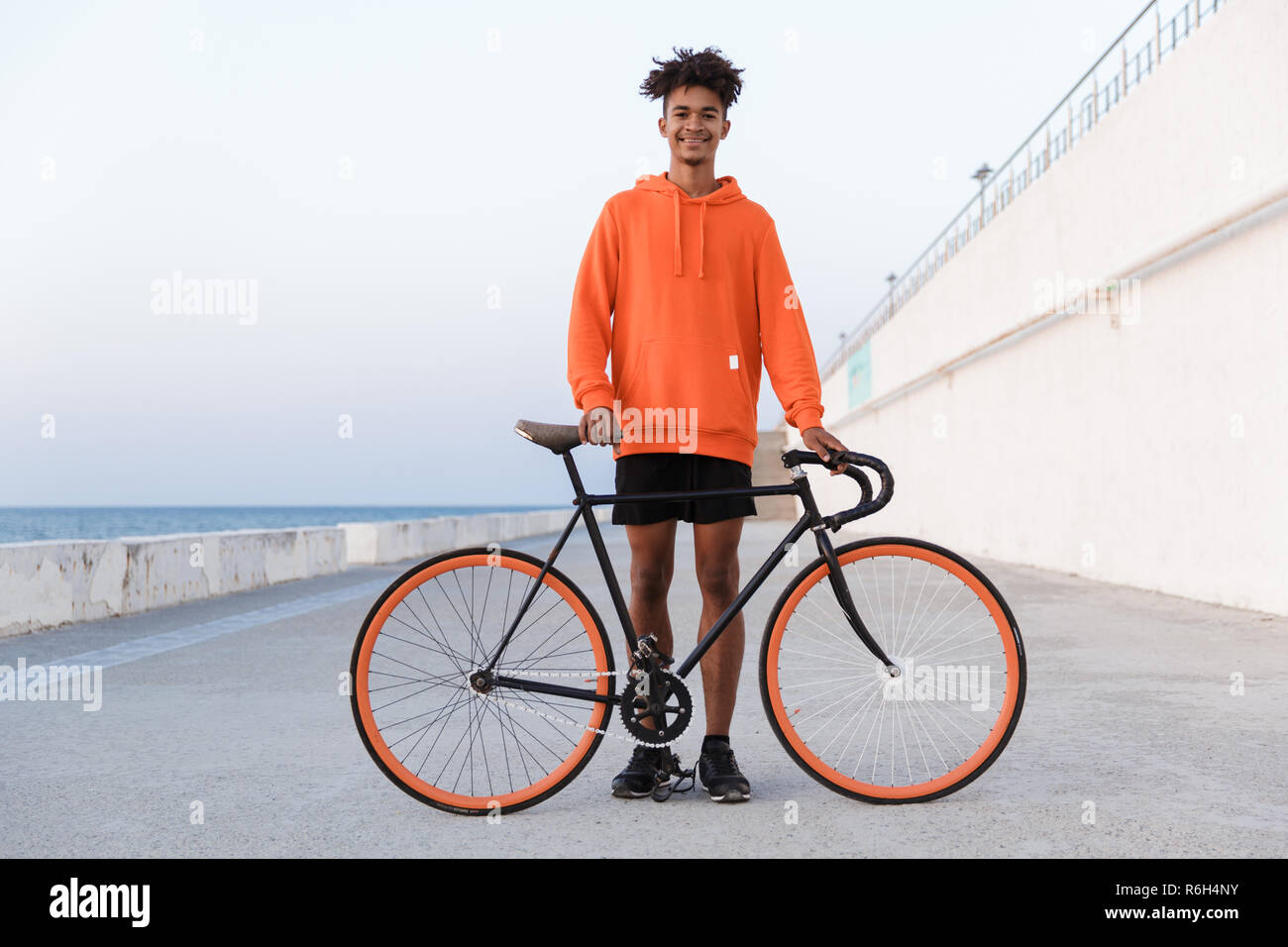 Image of a young happy cheerful sports guy outdoors on the beach with ...