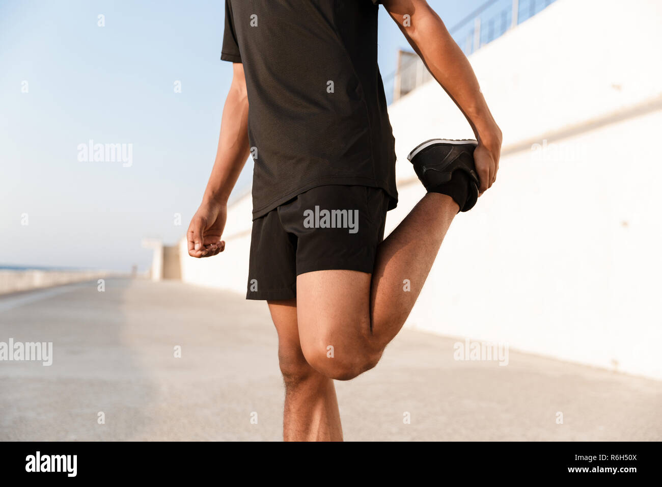 Cropped image of strong young guy sportsman make exercises outdoors on ...