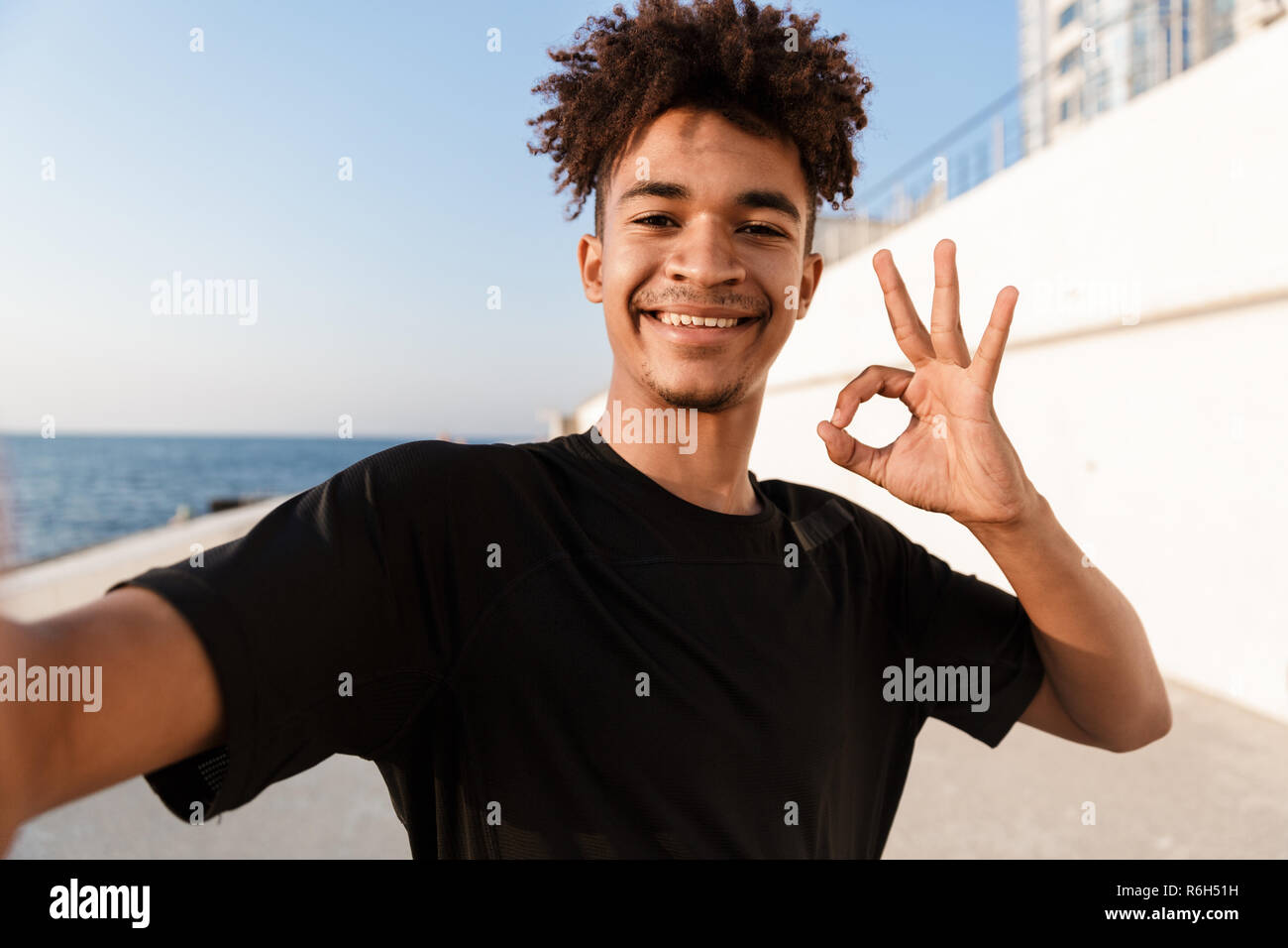 Image of handsome young guy sportsman standing outdoors on the beach ...