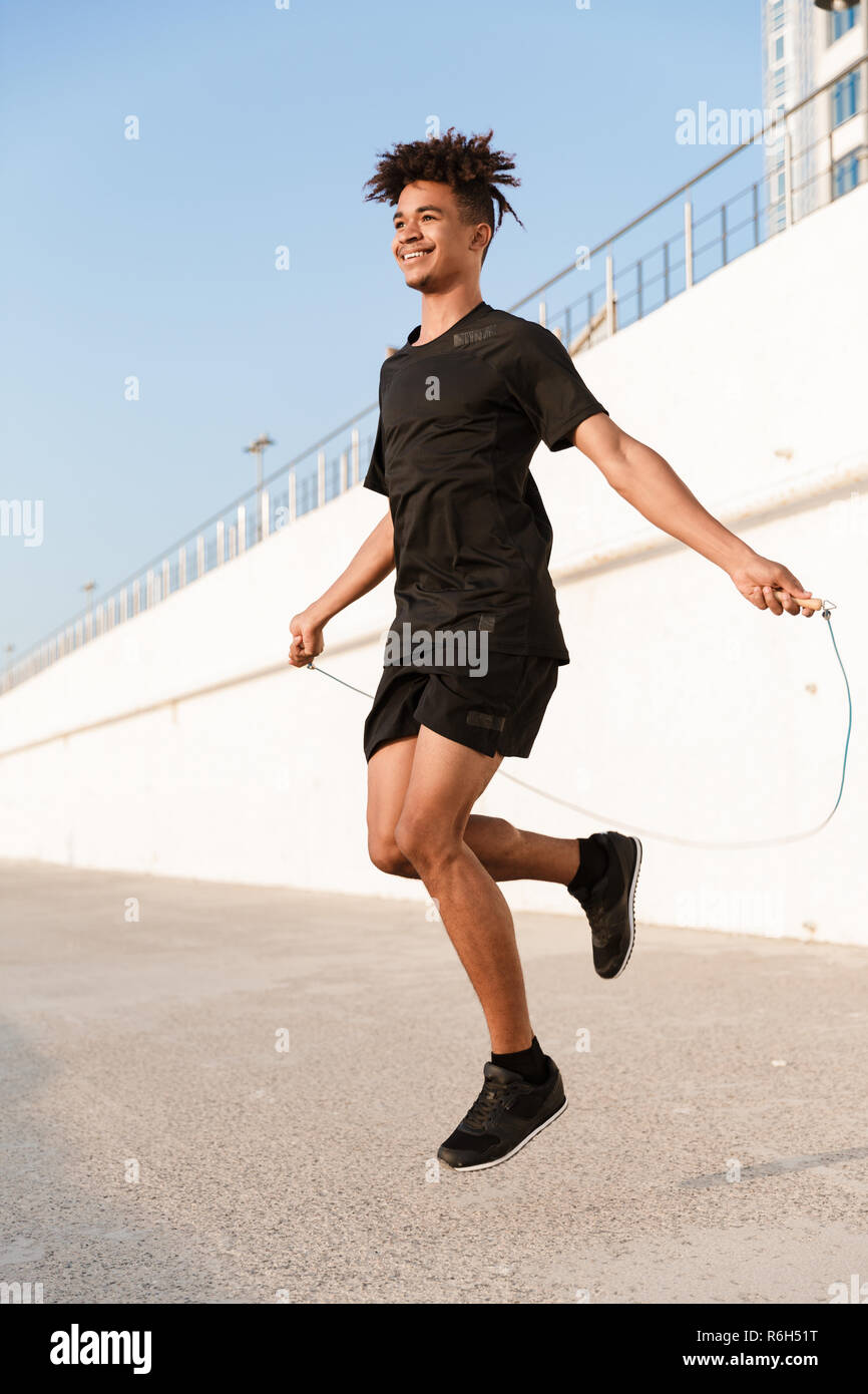 Image of handsome young guy sportsman jumping with skipping rope ...