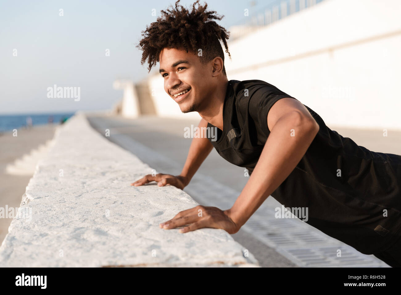Image of handsome young guy sportsman make exercises outdoors on the ...