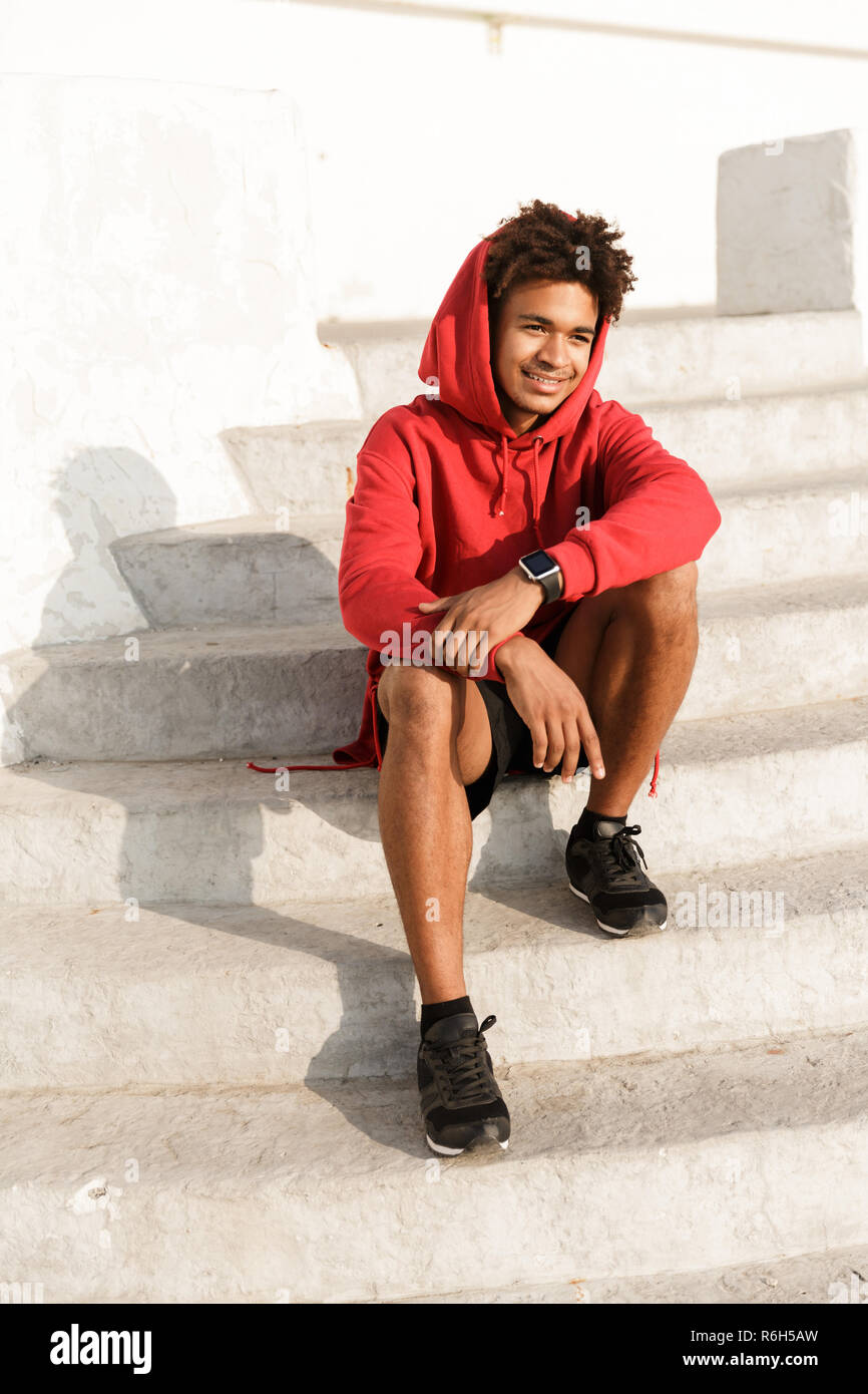 Image of a young guy outdoors on the beach sitting on steps posing ...