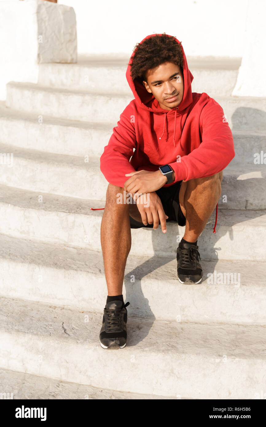 Image of a young guy outdoors on the beach sitting on steps posing ...