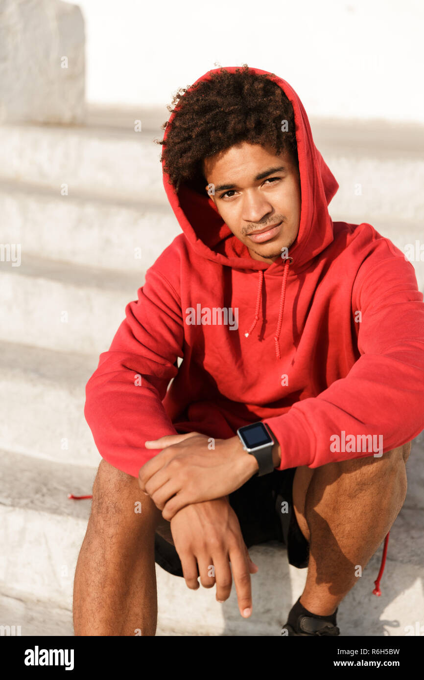 Image of a young guy outdoors on the beach sitting on steps posing ...