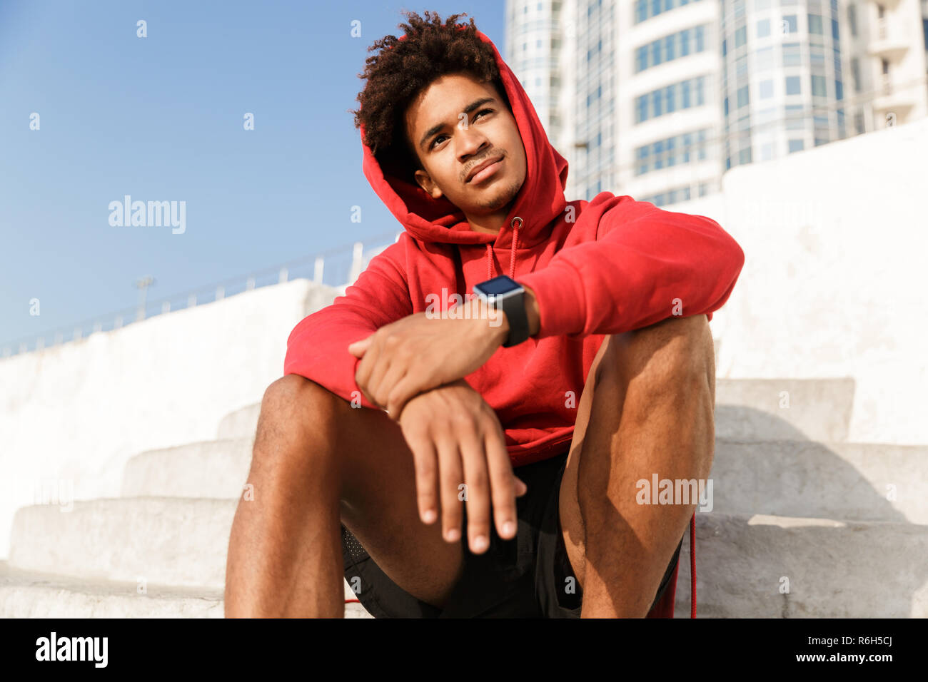 Image of a young guy outdoors on the beach sitting on steps posing ...
