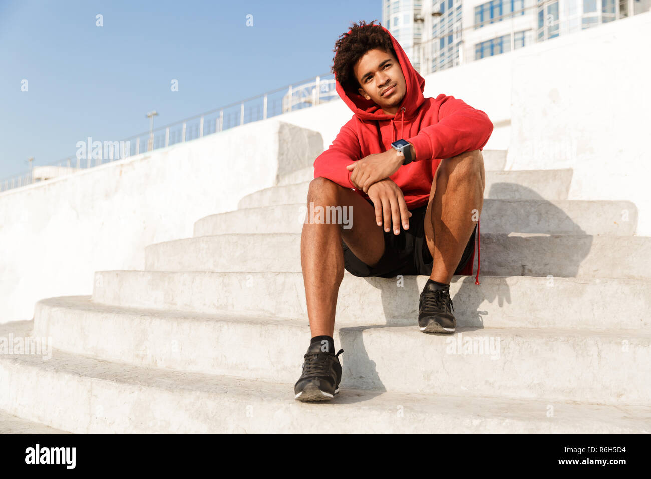 Image of a young guy outdoors on the beach sitting on steps posing ...