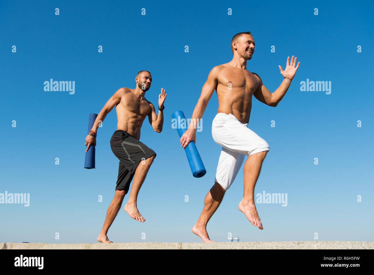 Forward to healthy lifestyle. Men with yoga mat captured in motion blue ...