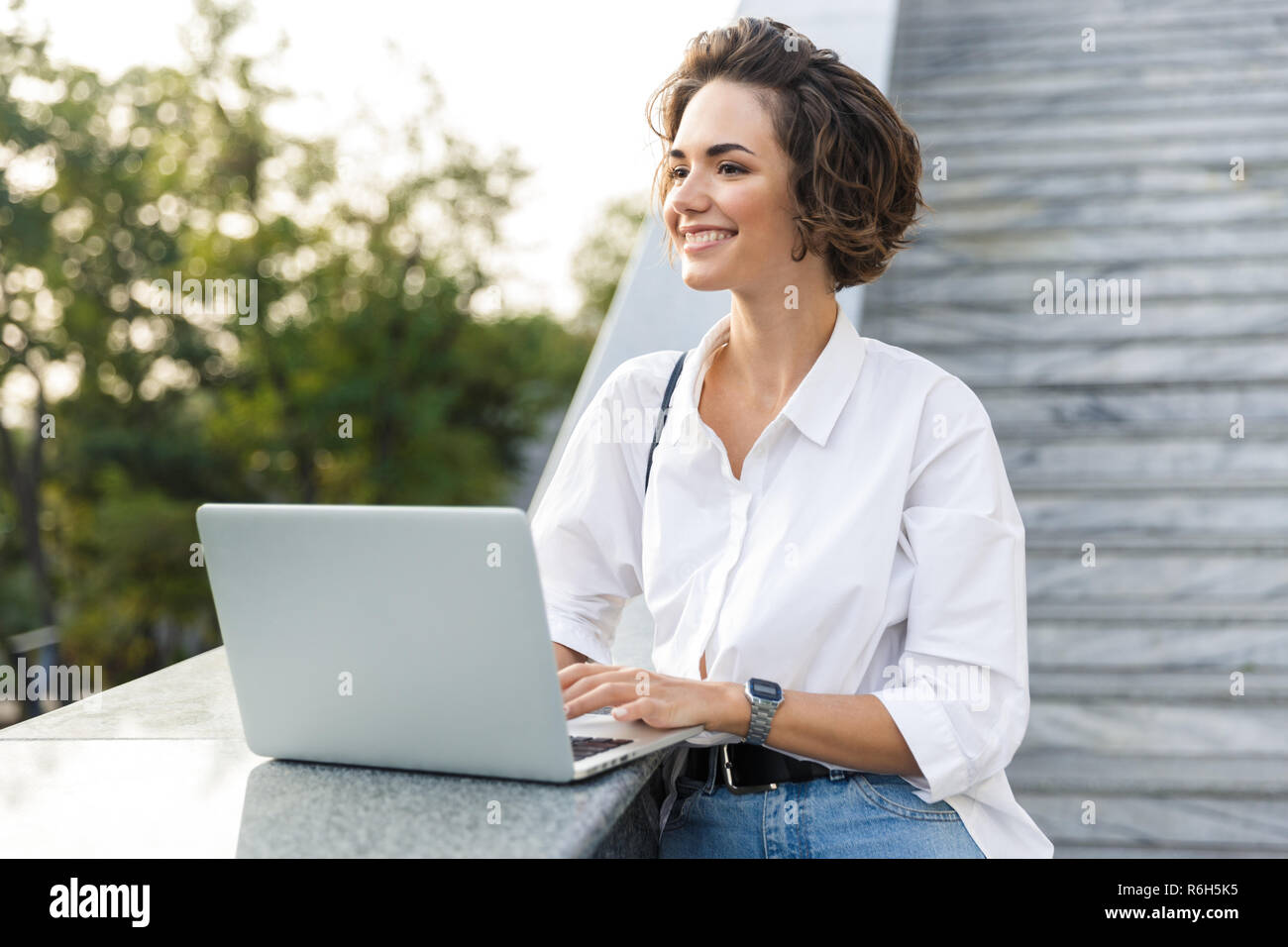 Picture of young cute beautiful woman walking outdoors using laptop ...