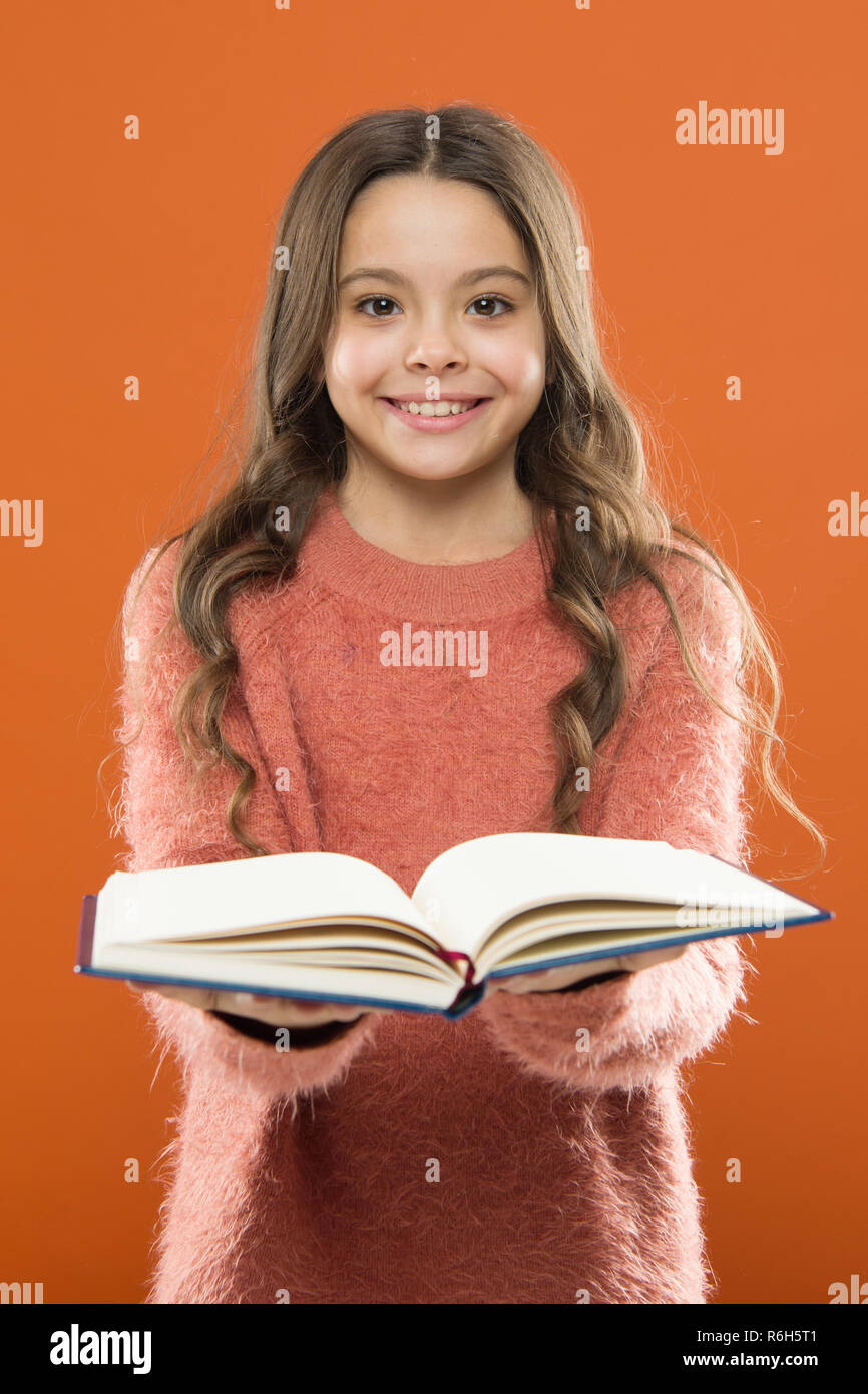 Girl hold book read story over orange background. Child enjoy reading ...
