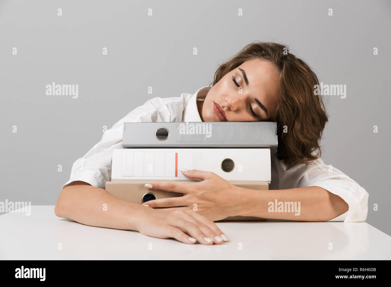 Photo of a bored tired young woman sitting at the table isolated over ...