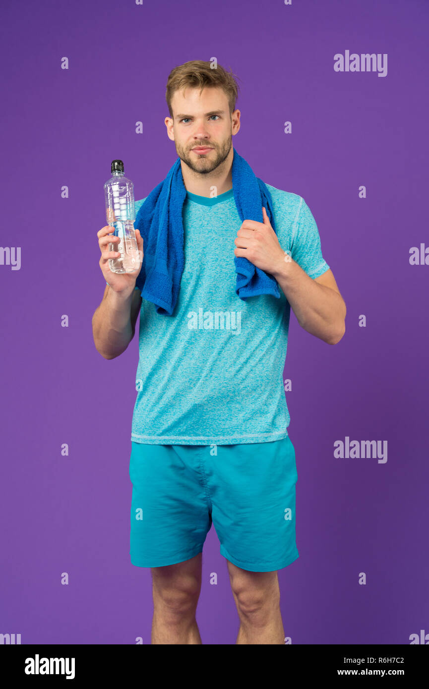 Stay hydrated. Man with towel on shoulders hold bottle. Athlete drink ...