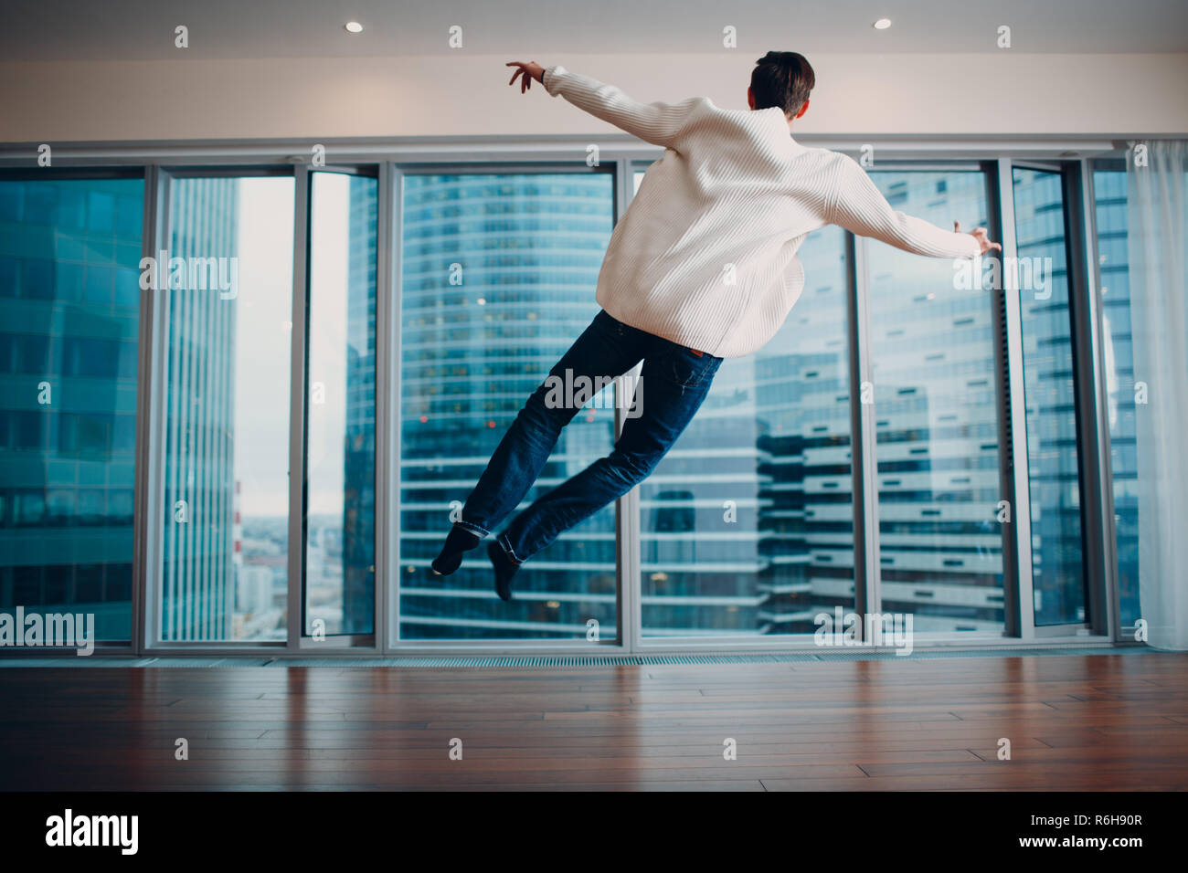 Jumping young man on the background of a skyscraper indoors Stock Photo ...