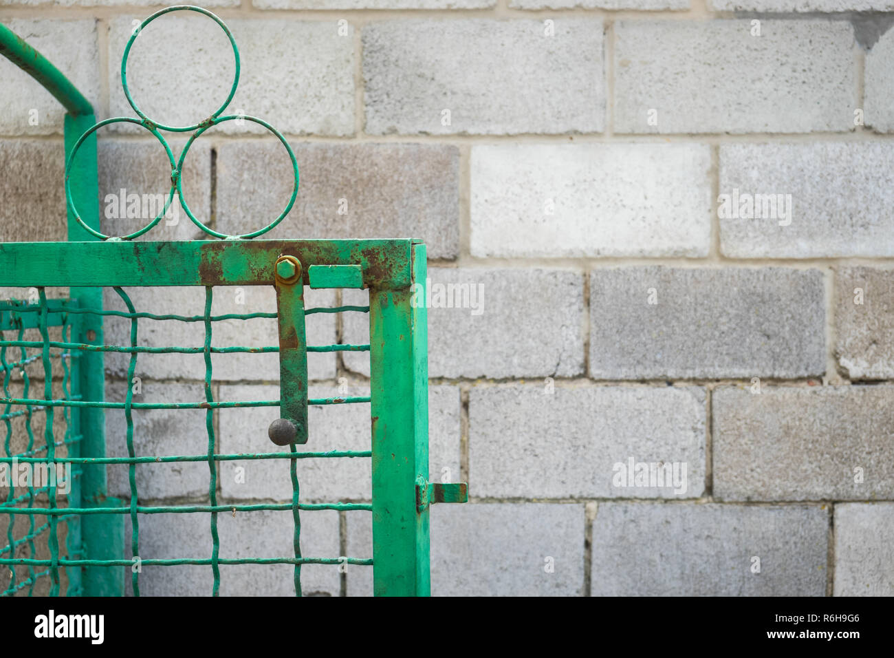 open green gate and welded mesh fence against a wall of cinder block ...