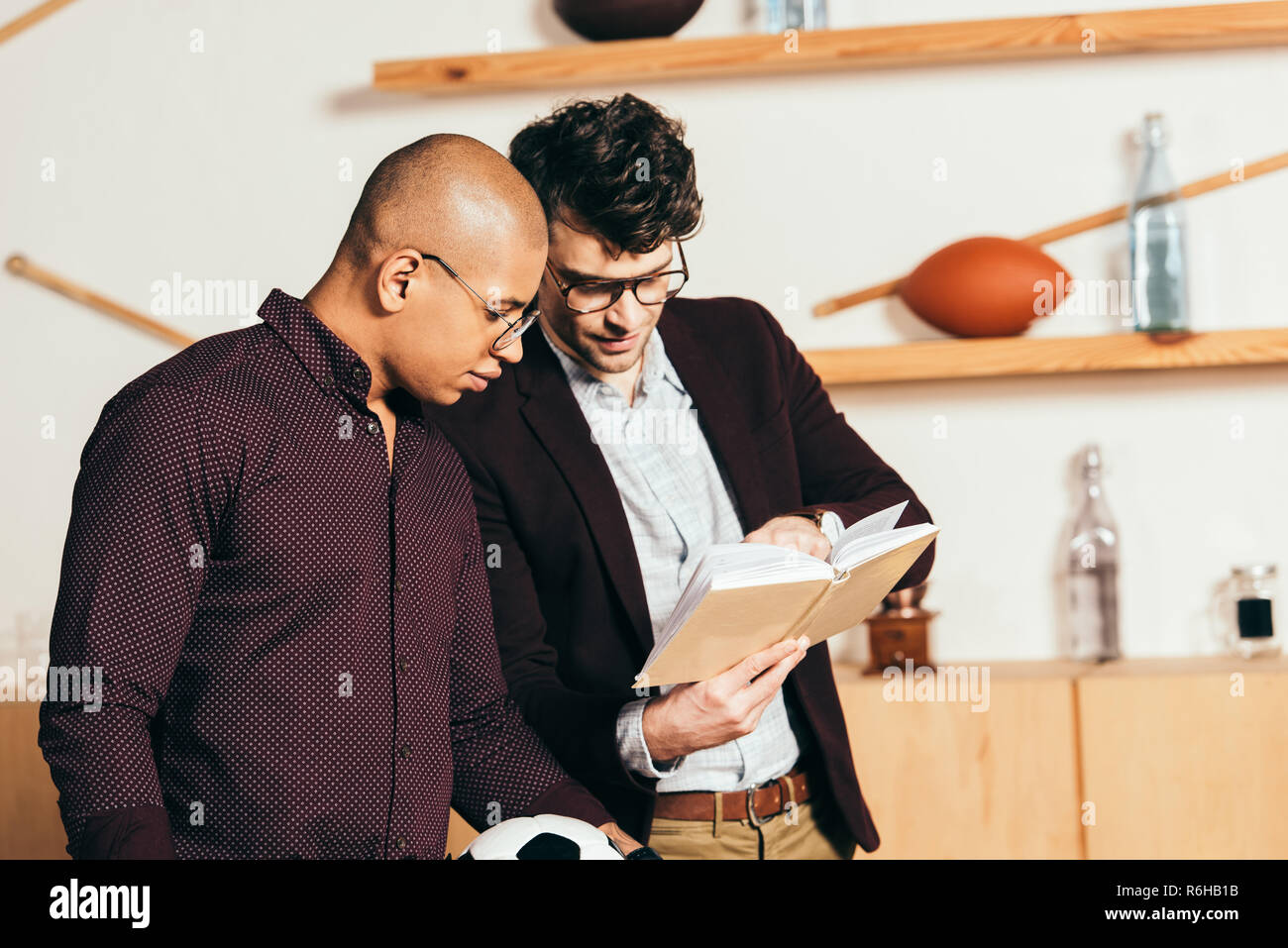 portrait of multiracial businessmen reading book together in cafe Stock ...