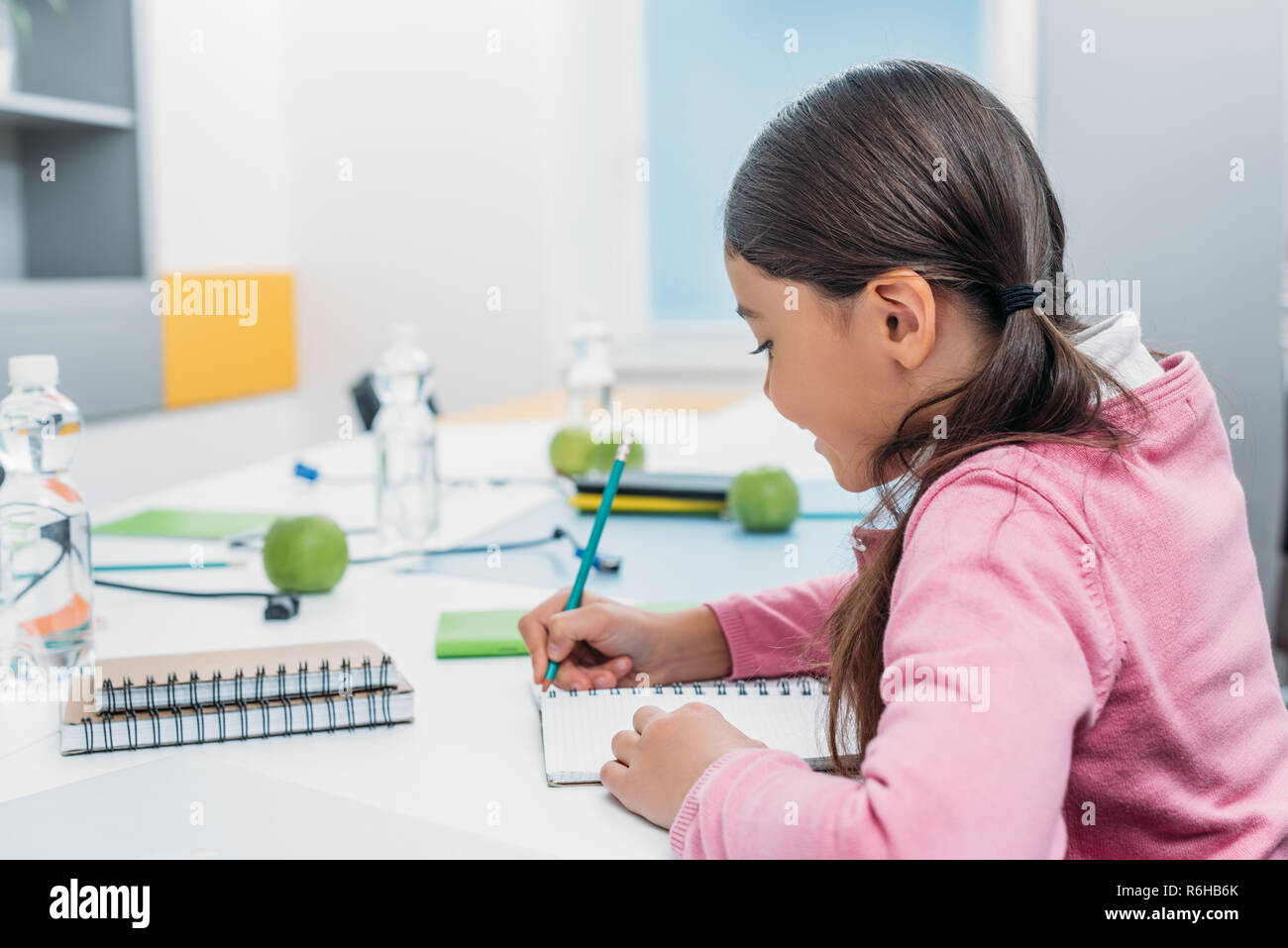schoolgirl writing in notebook during lesson in classroom Stock Photo ...